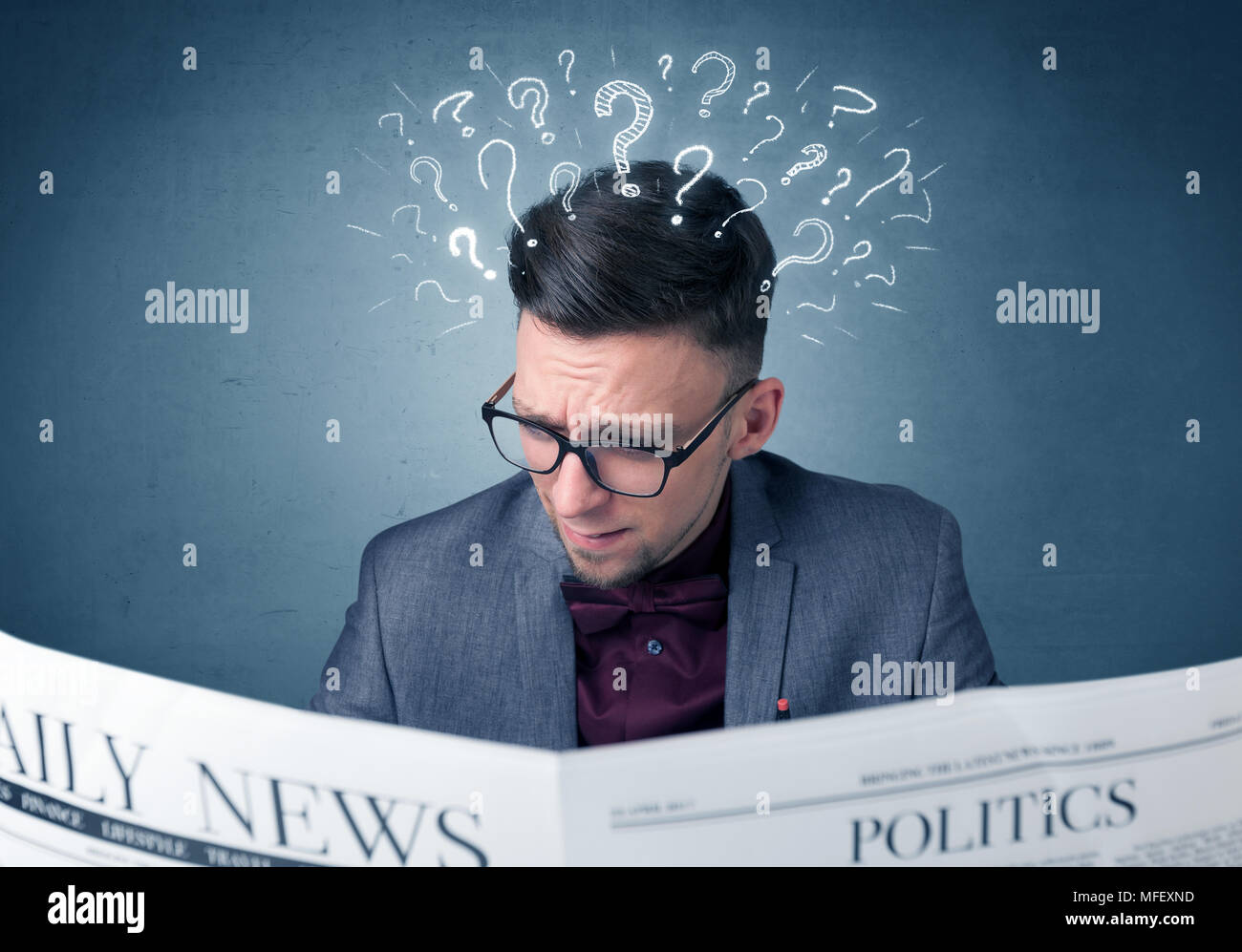 Young confused businessman reading daily newspaper with question marks ...