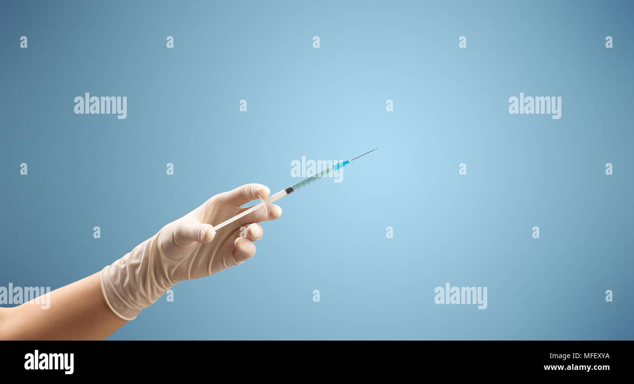 Female doctor hand holding syringe with blue background Stock Photo - Alamy