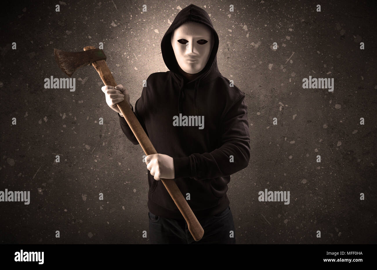Masked armed villain in empty dark room with gun ax chainsaw mallet ...