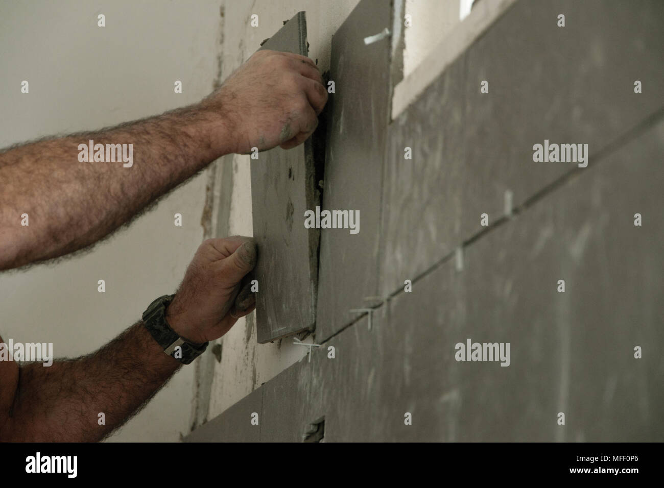 Close Up of professional mason worker indoor - laying tiles on wall at ...
