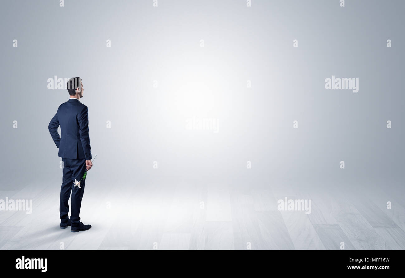 Man standing with his back in an empty room with object in his hand ...