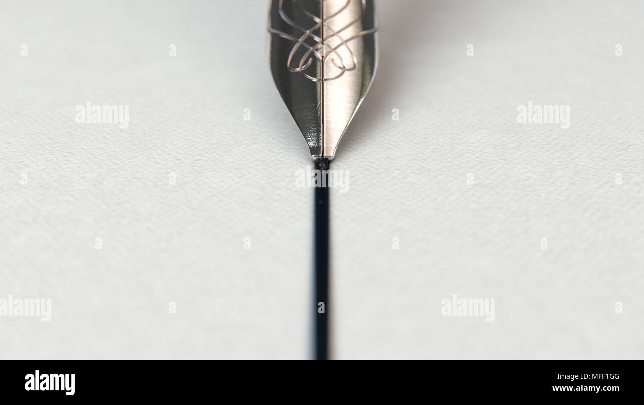 A closeup view of an ornate metal nib of an old fountain pen drawing a ...