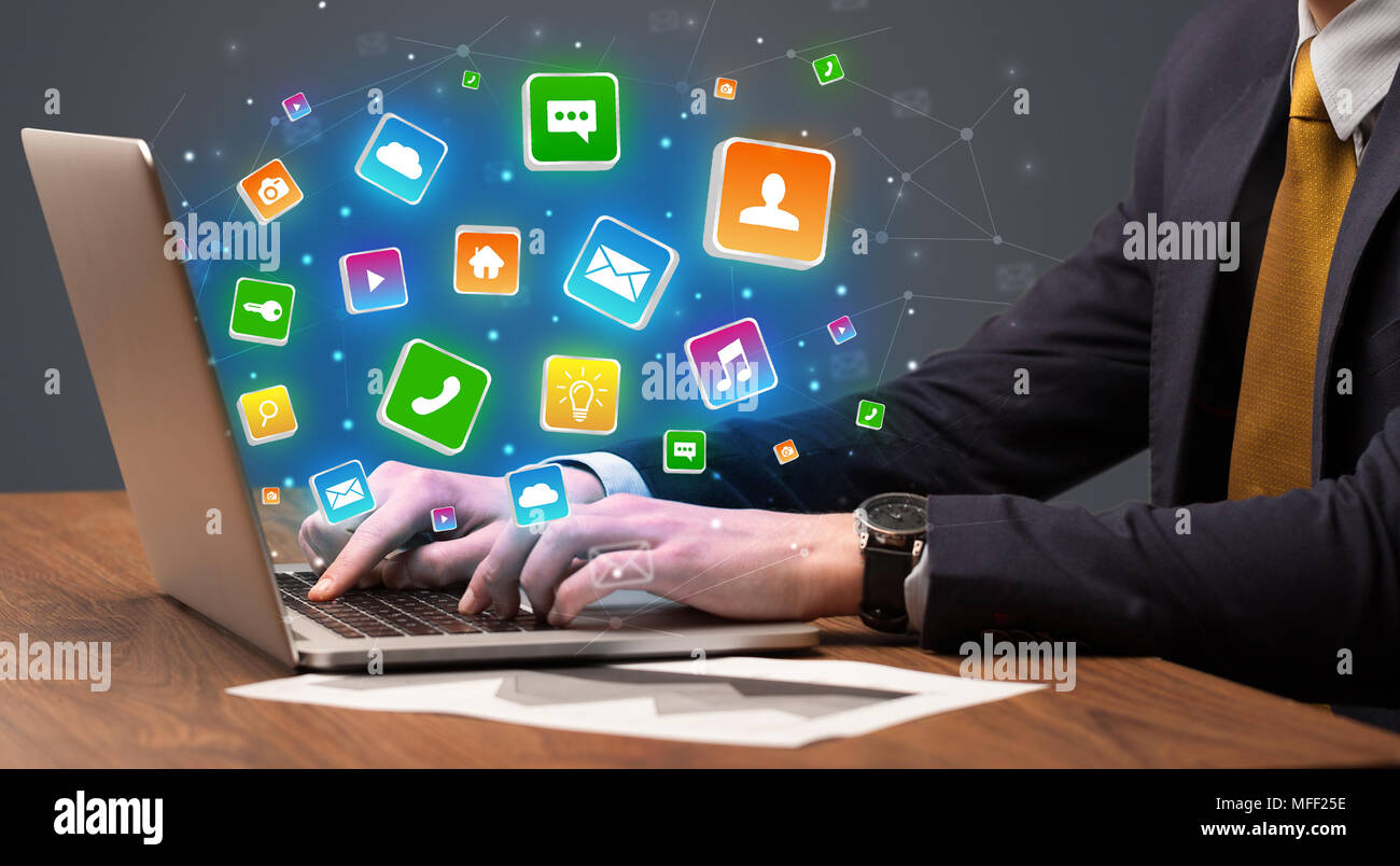 Businessman hand typing on laptop with flying application icons around ...