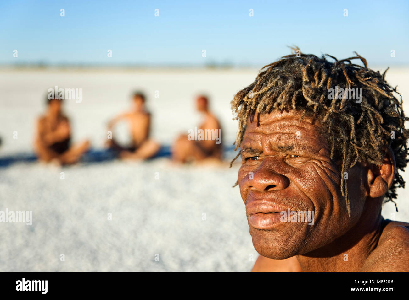 Bushmen dressed in traditional skins, sitting in a half circle on the ...