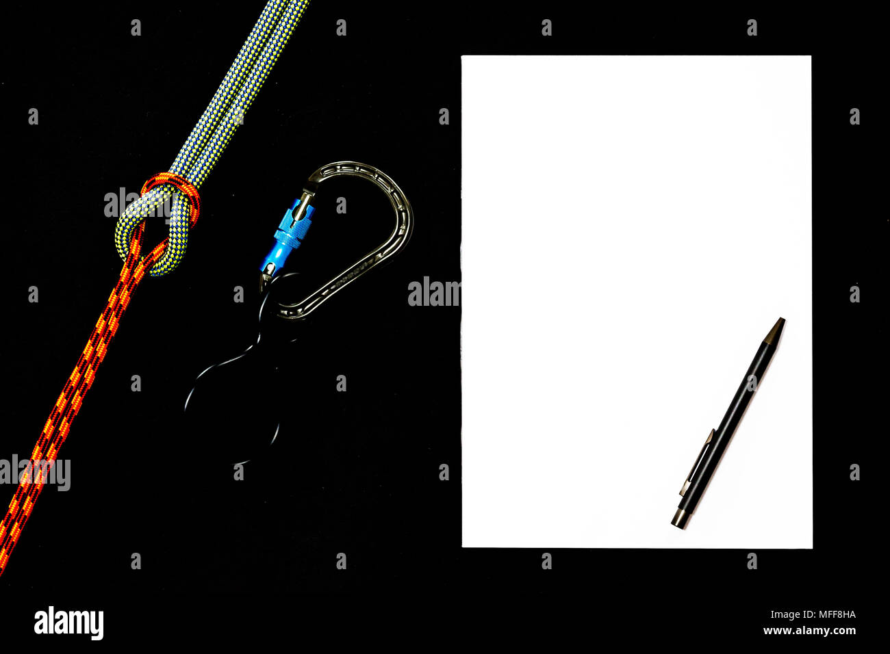 top view of office desk with blank notebook paper pen rope carabiner ...