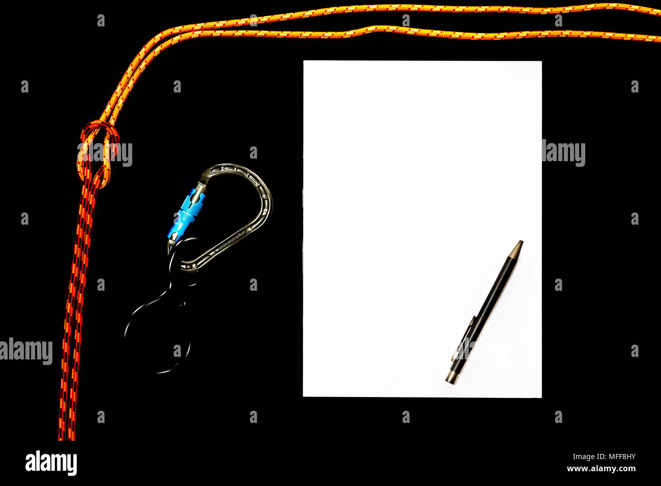 top view of office desk with blank notebook paper pen rope carabiner ...