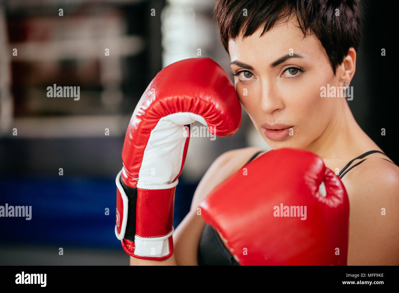 determined woman with black short hair is practising boxing moves in ...