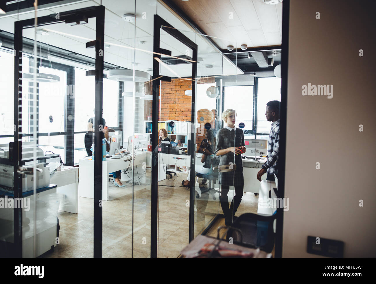 industrious young people who work in the modern office with glass walls ...