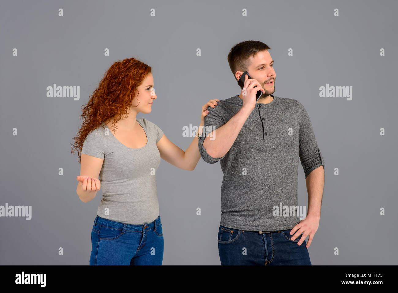 A handsome young guy standing and talking on his phone and ignoring his ...