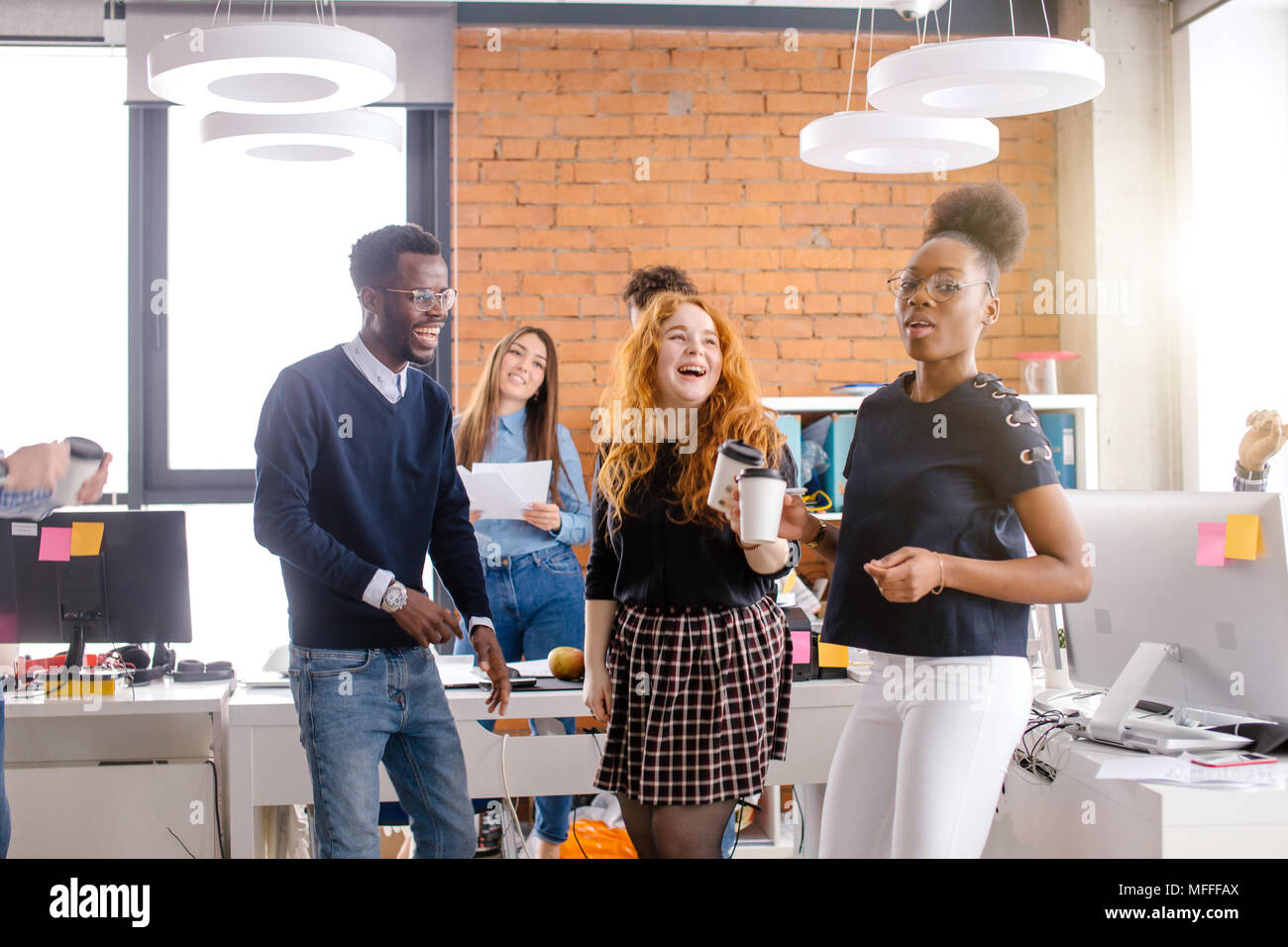 smiling young managers are drinking tea in break time at workplace ...