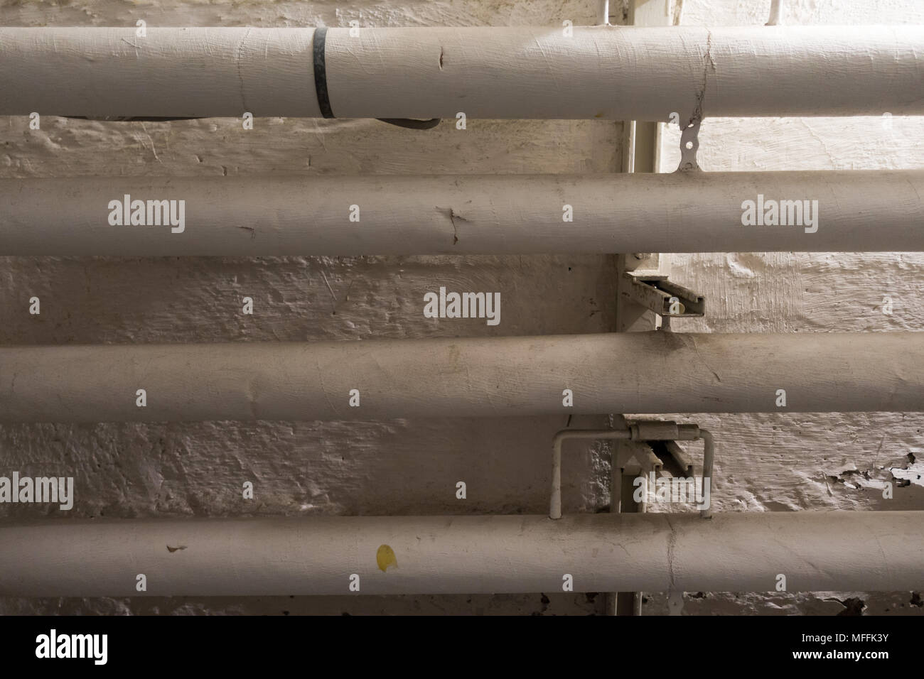 Pipes running across the wall in a basement Stock Photo - Alamy