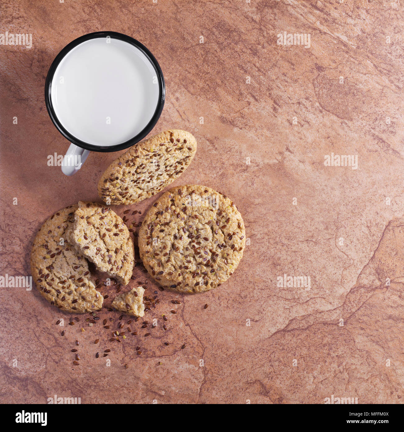 Cookies with flax seeds and sesame and enamel mug with milk against the ...