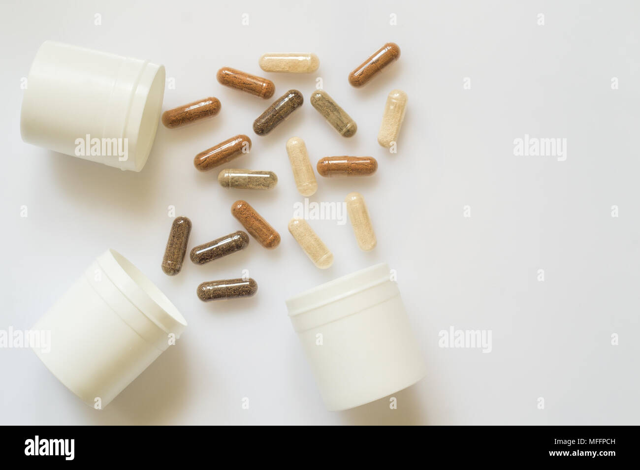 Medicinal capsule spill out of a three plastic bottles on a light ...