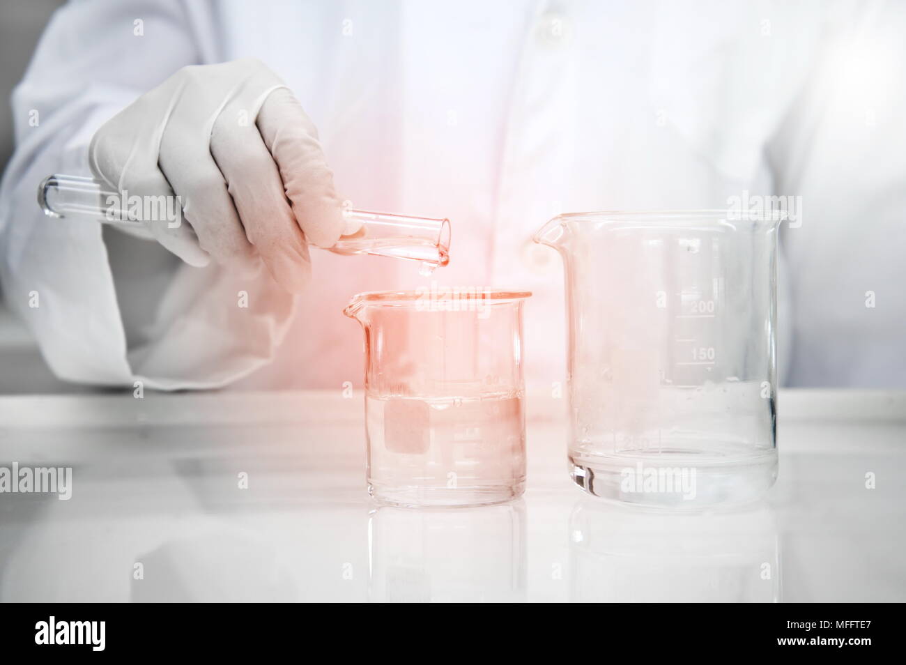 researcher in white lab coat holding cylinder and poring water into ...
