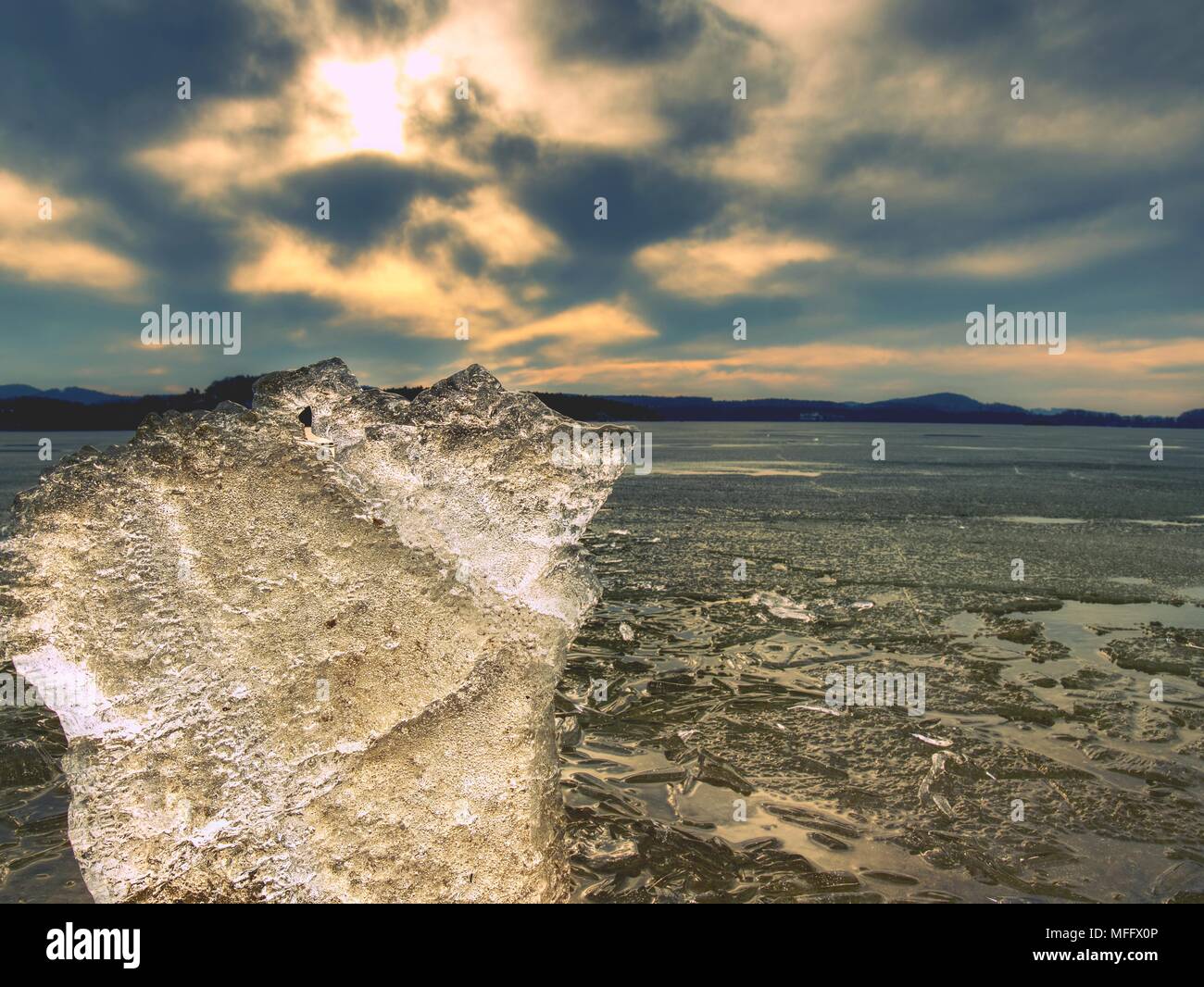 Ice melting on sandy beach. Detail of ice floe with deep cracks inside ...