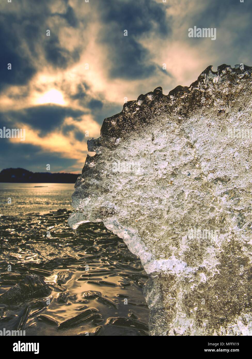 Icy sheets melting on sandy beach. End of long and crue winter coming ...