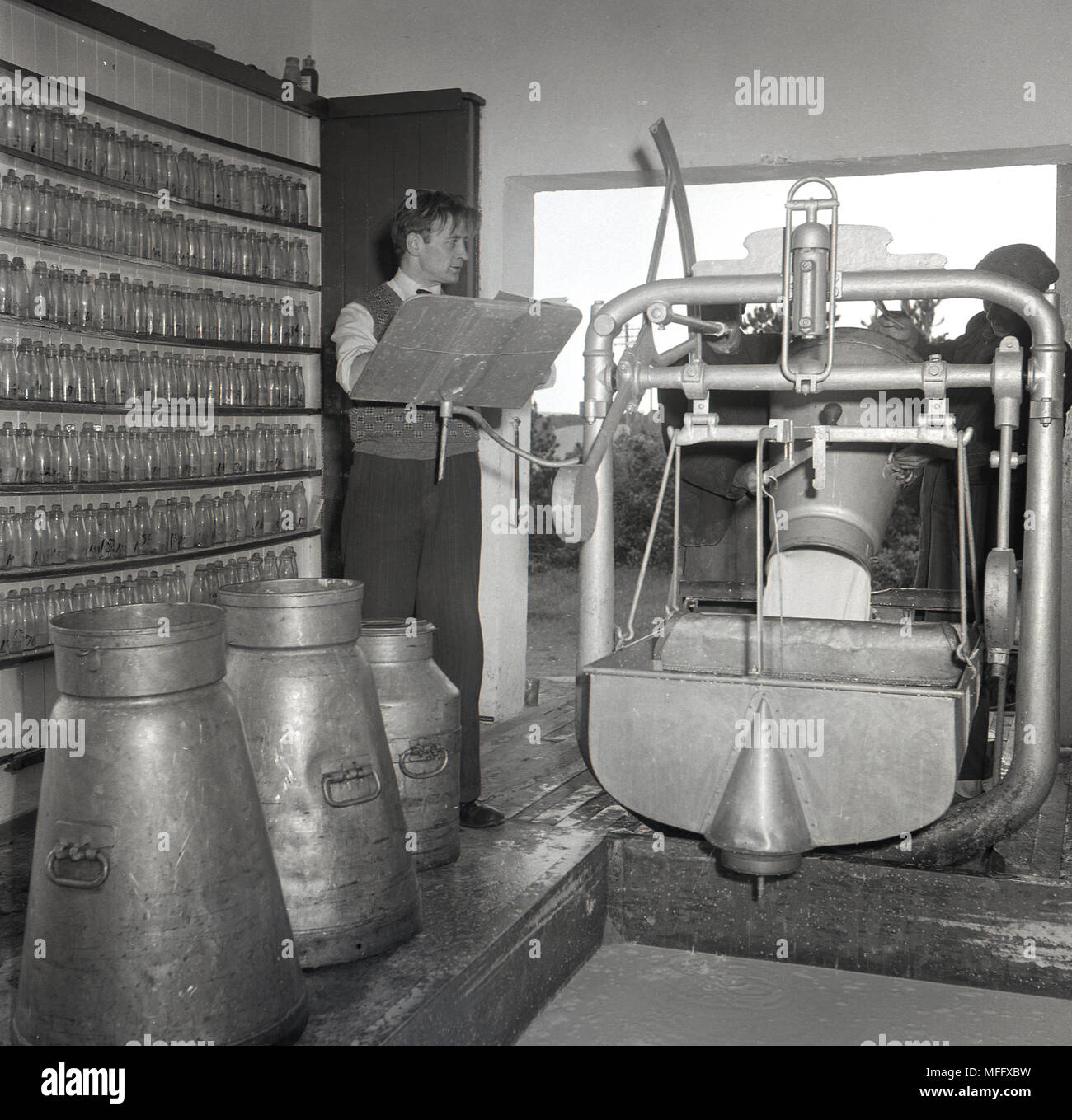 1950s, historical, dairyman noting down the quantity of milk being ...
