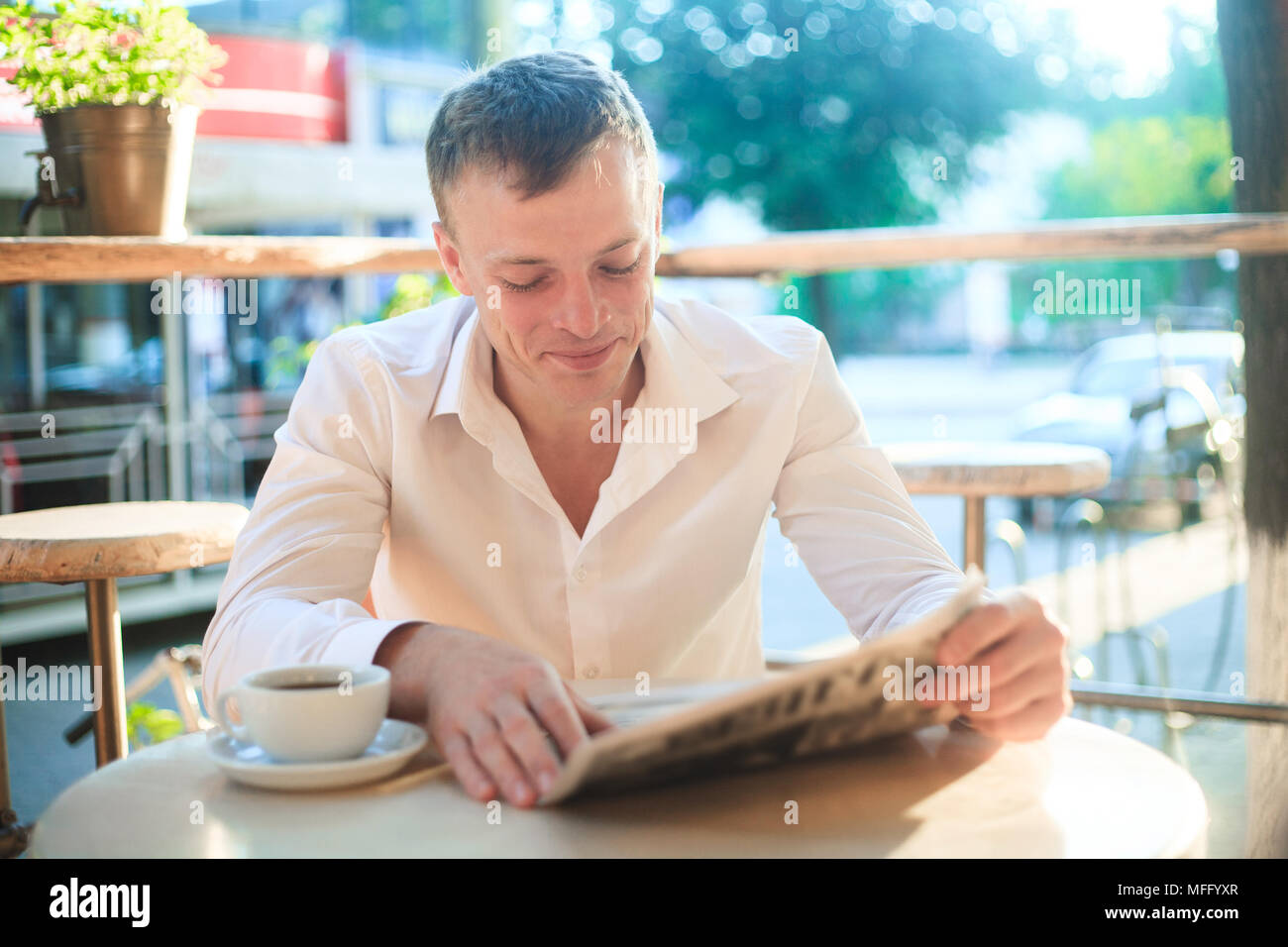 Thoughtful man reading a newspaper in a street cafe at lunch. Concept ...