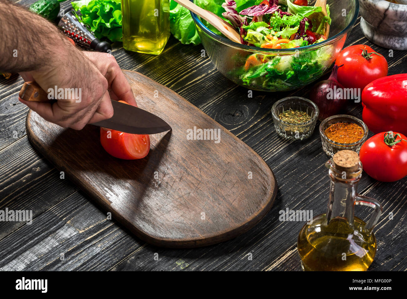Man's hand cuts ripe red tomatoes for summer healthy vegetable salad on ...