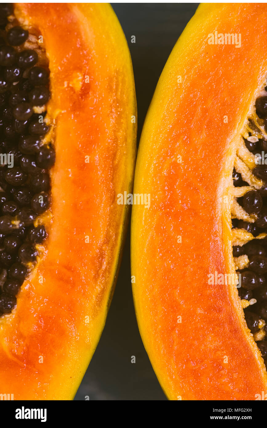 Close up of tropical fruit papaya cut i half on a wooden background ...