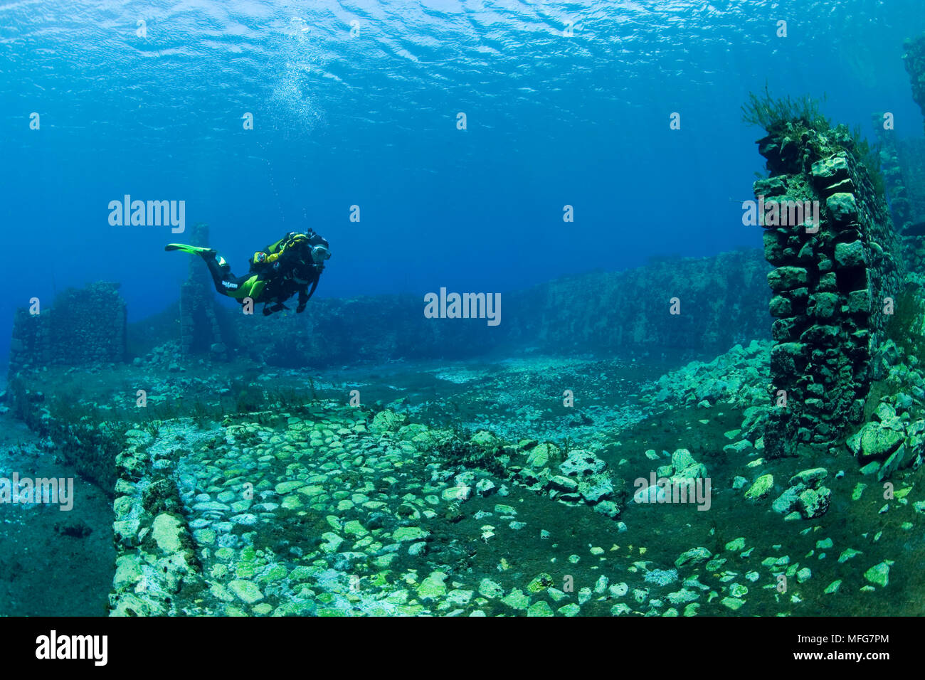 Scuba diver swimming over a old road, between walls of the underwater ...