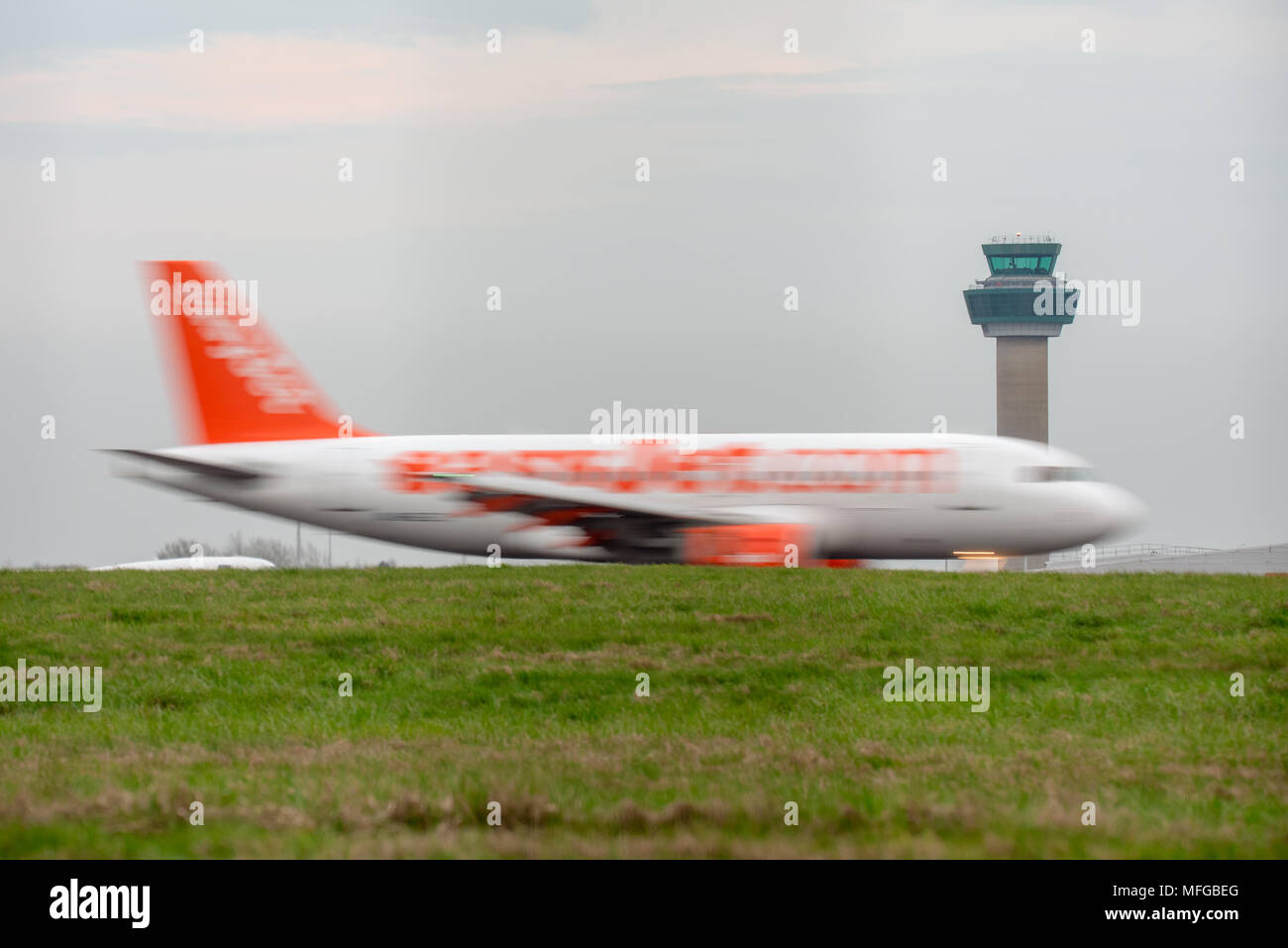 A small to medium EasyJet airplane speeds along a runway with motion ...