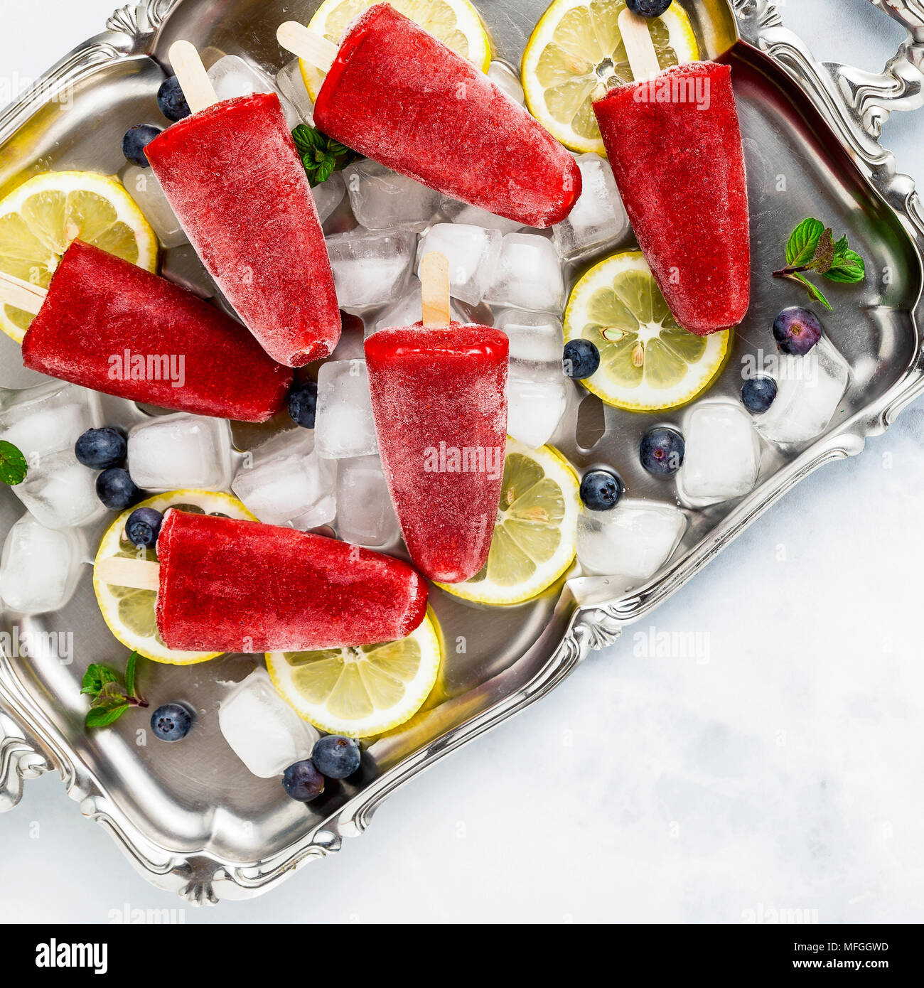 frozen strawberry juice snack ice pop or popsicle on a white marble ...