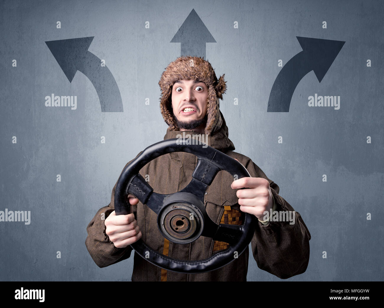 Young man holding black steering wheel with three arrows above his head ...