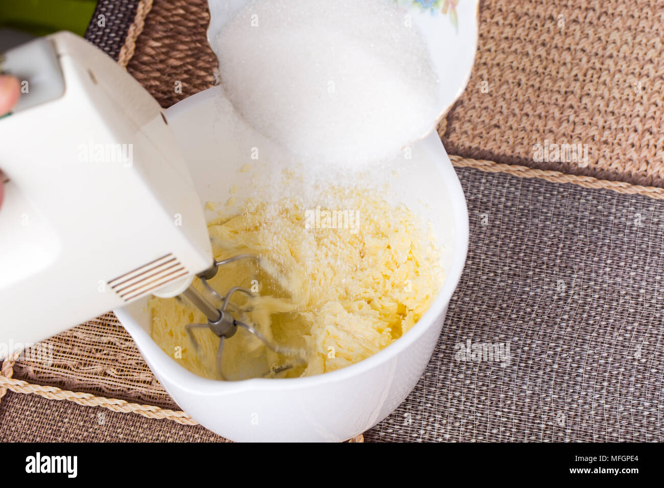 Mixing butter with sugar in white bowl for baking cake. On table as a ...