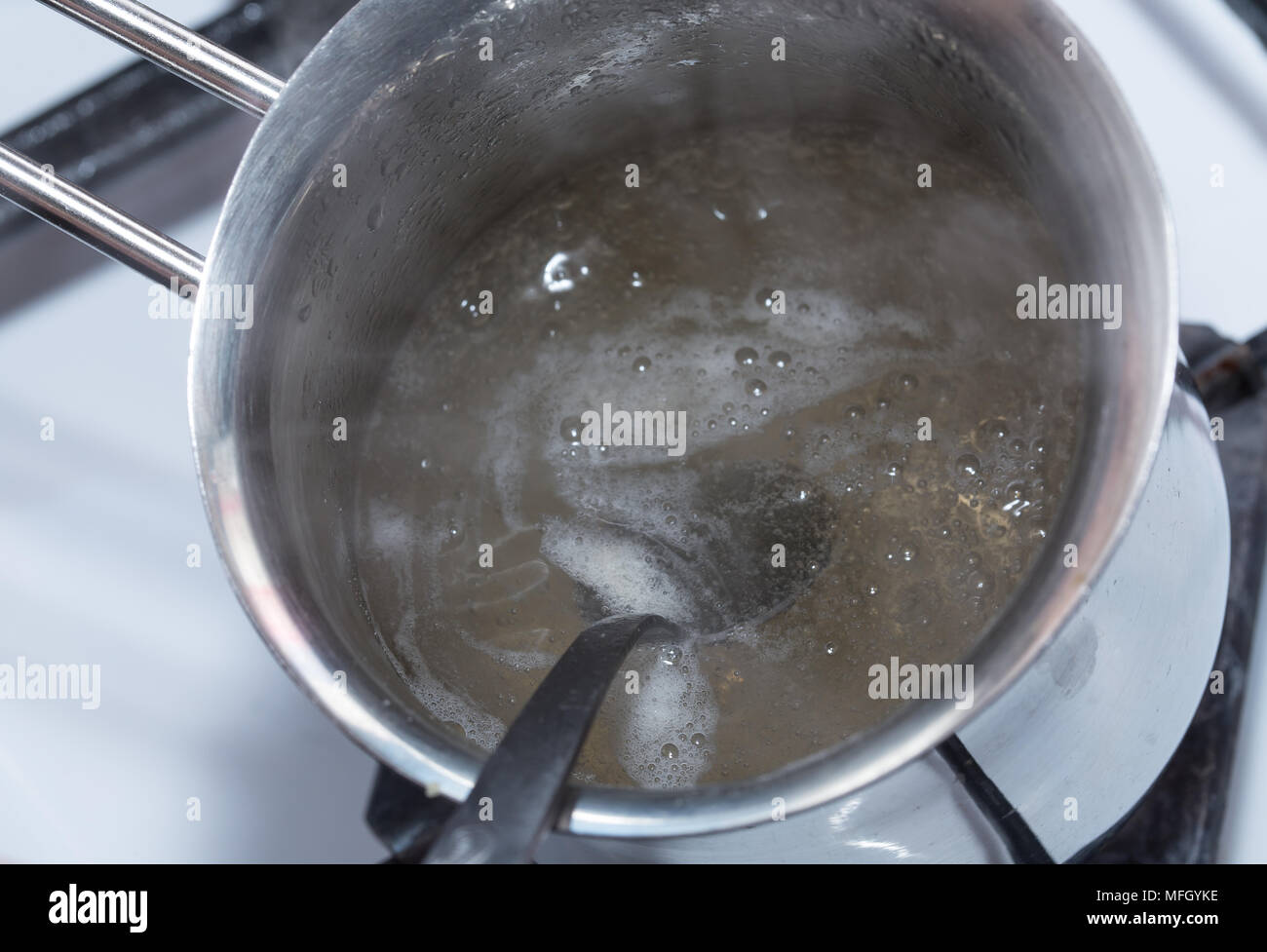 Melted gelatin in metal pot on the stove. Macro. Photo can be used as a ...