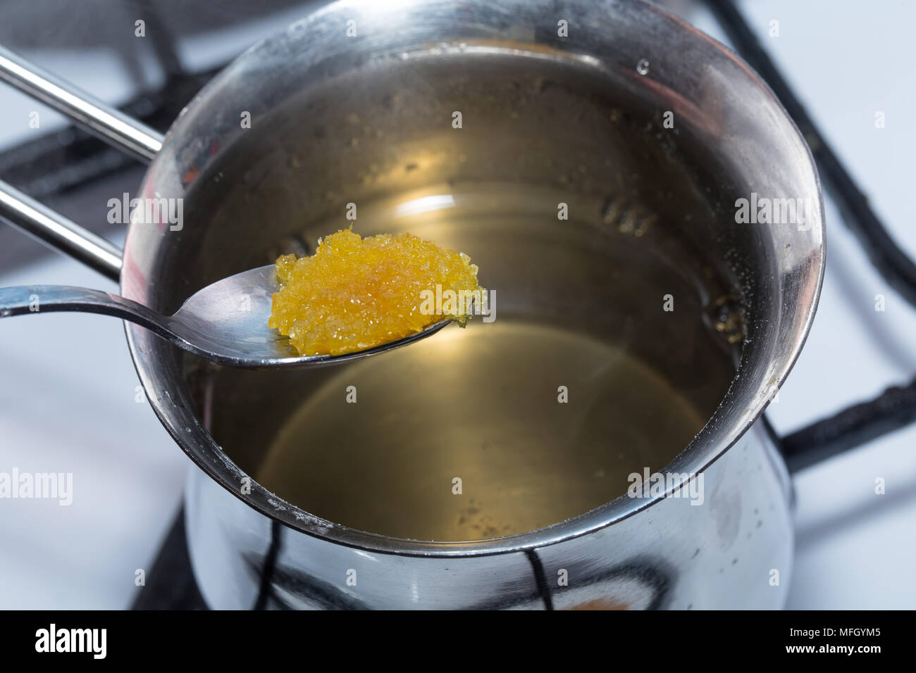 Adding brown sugar to melted gelatin in metal pot. Macro. Photo can be ...