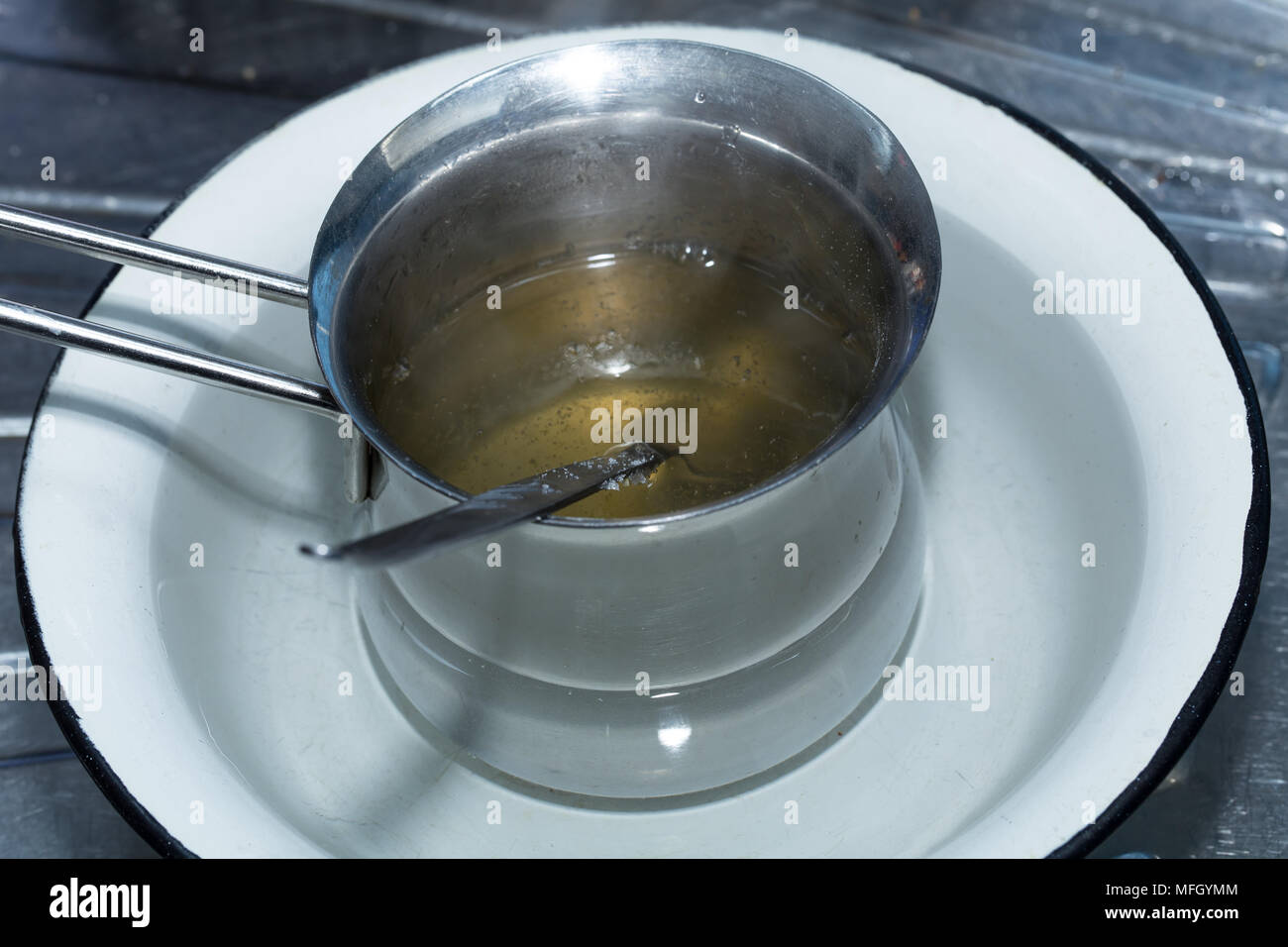 Melted gelatin in metal pot on the stove. Macro. Photo can be used as a ...