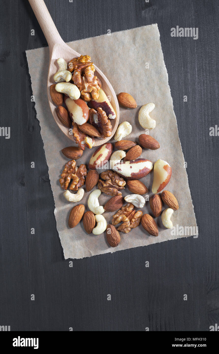 Assorted mixed nuts with spoon on an black wooden table, top view ...