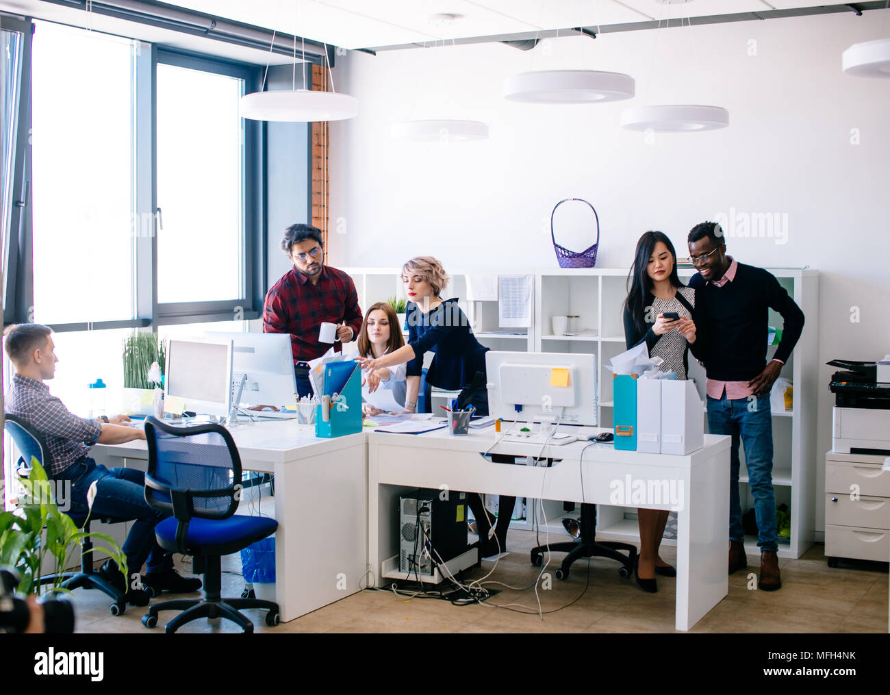 crowded office with young active employees. everybody is doing his ...