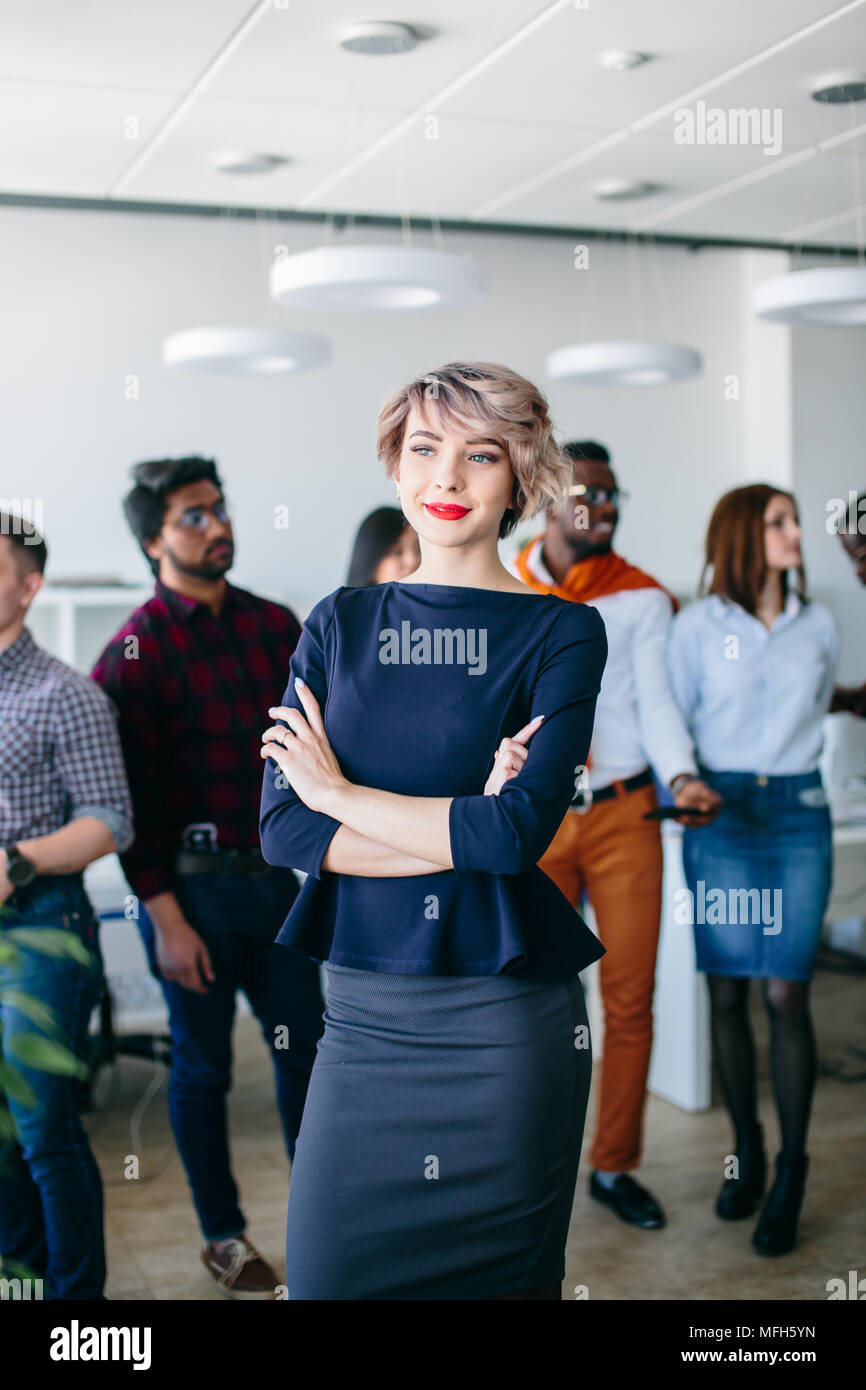 smiling female CEO with beautiful makeup standing with arms folded in ...