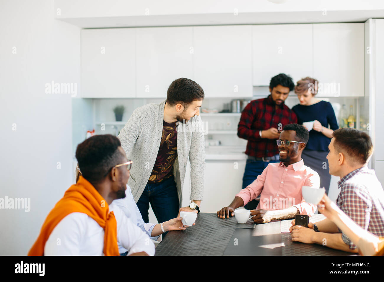 friendly conversation among diverse office workers over a cup of tea ...
