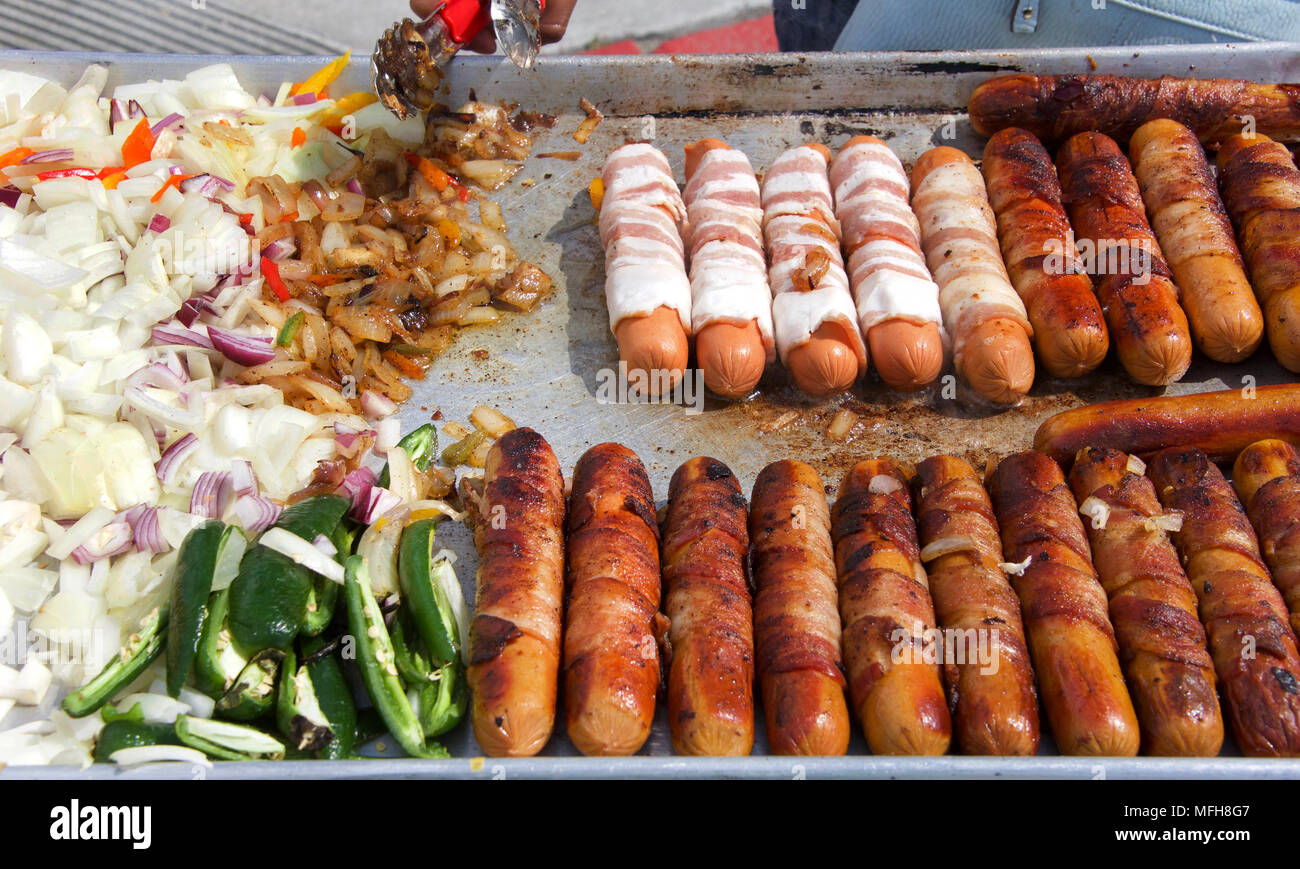 Street vendor cooking bacon wrapped hot dogs with onions and jalapeno ...