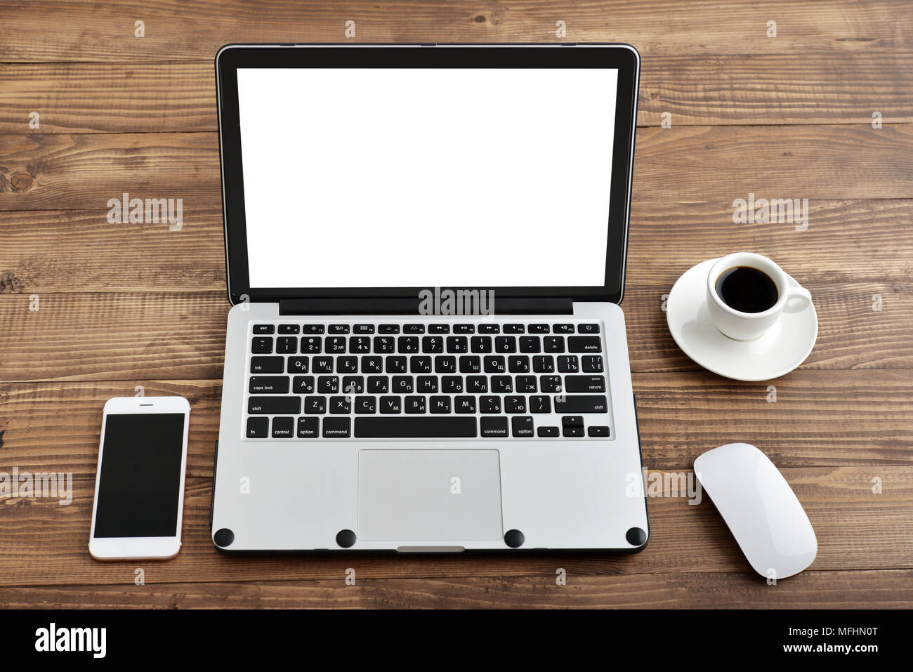 Laptop with blank screen, computer mouse, smartphone and cup of coffee ...