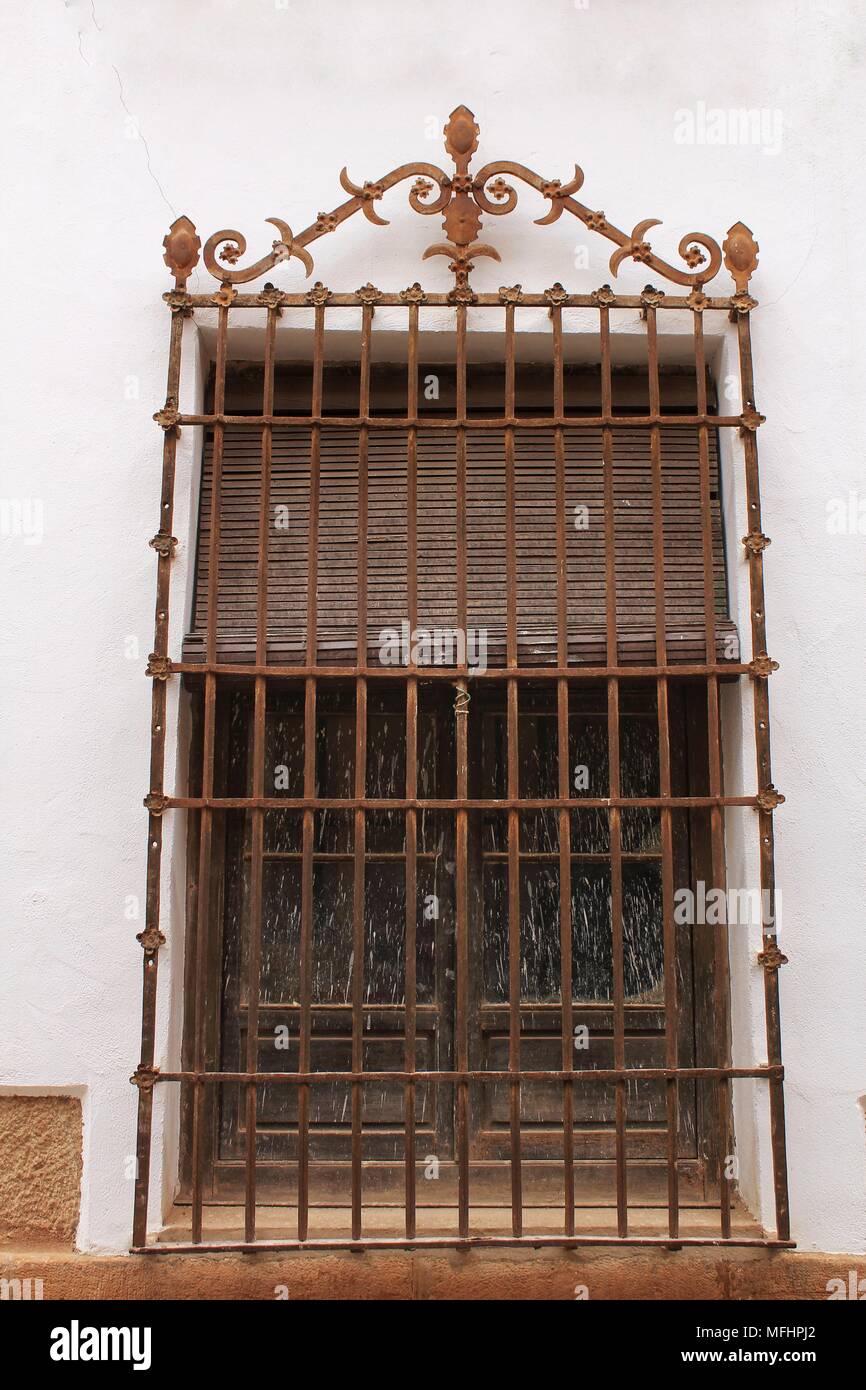 Old rusty wrought iron window on white facade in a house of Villanueva ...