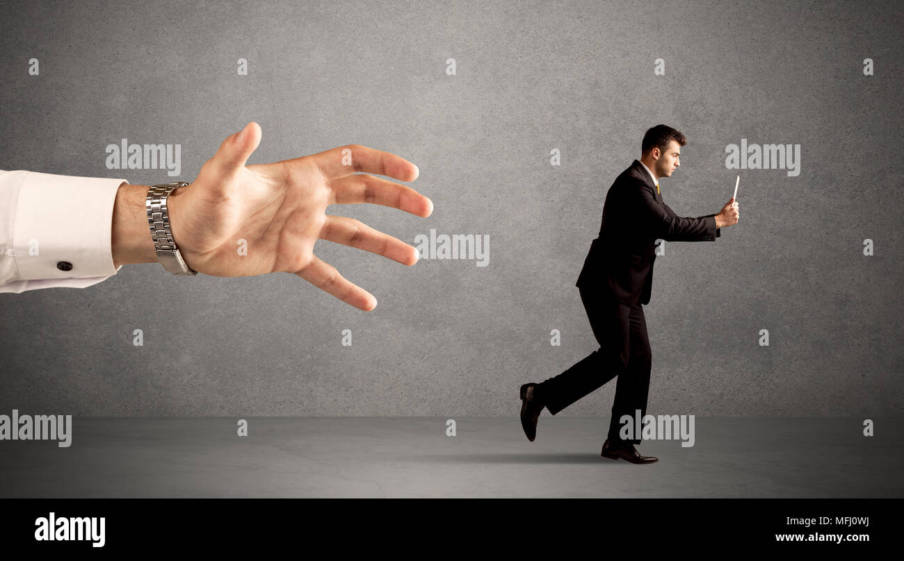 Young miniature businessman running from a big hand with light grey ...