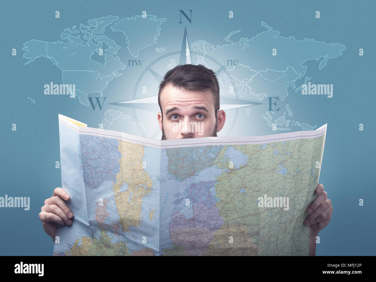 Handsome young man holding a map with a world map and a compass behind ...