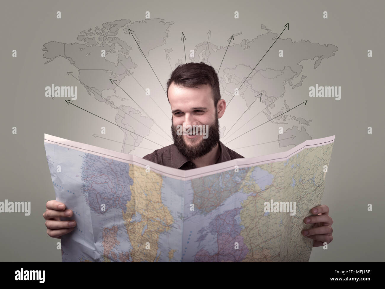 Handsome young man holding a map with world map and arrows behind him ...