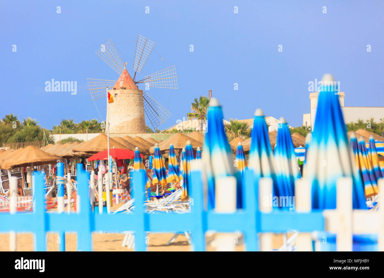 Beach umbrellas and windmill, Baia dei Mulini, Trapani, Sicily, Italy ...