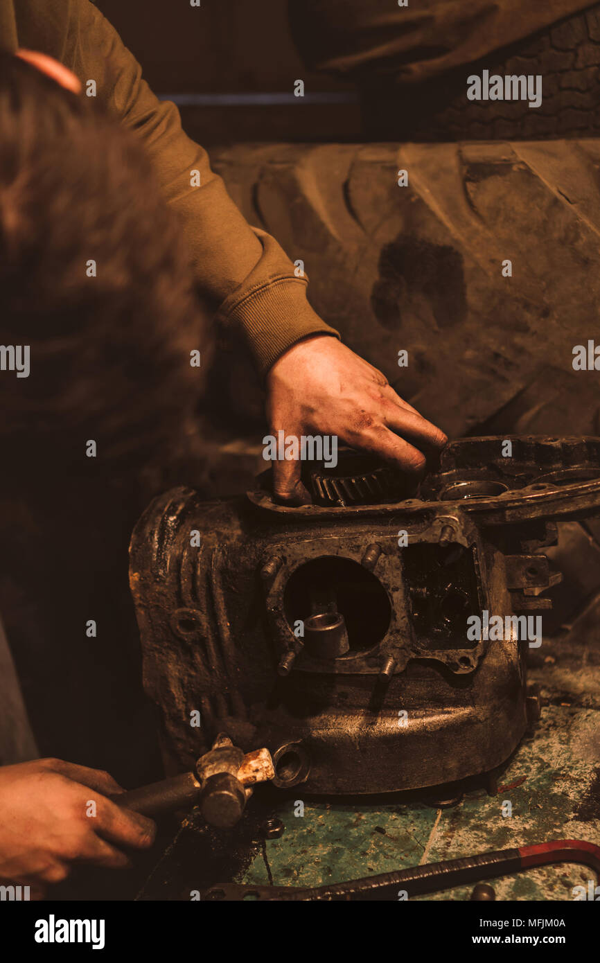 Motorcycle engine disassembly. Man knocks rusty detail with a hammer ...