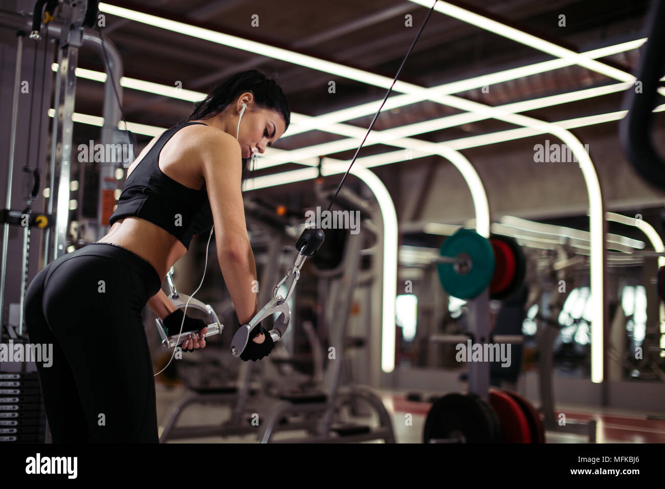rear view fit woman exercise with exercise-machine Cable Crossover in ...