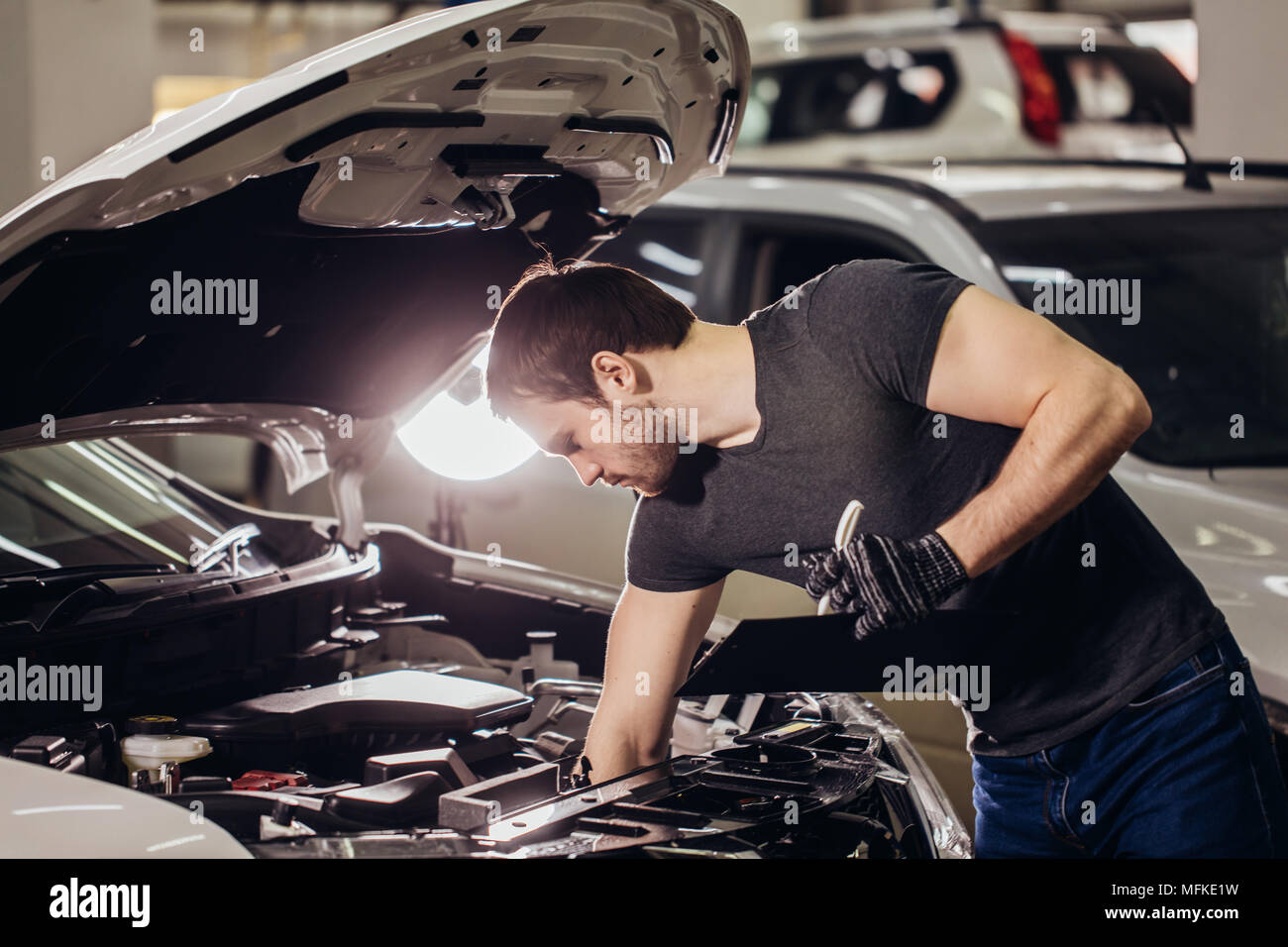 Mechanic perform vehicle checkup and make notes in notepad in garage ...