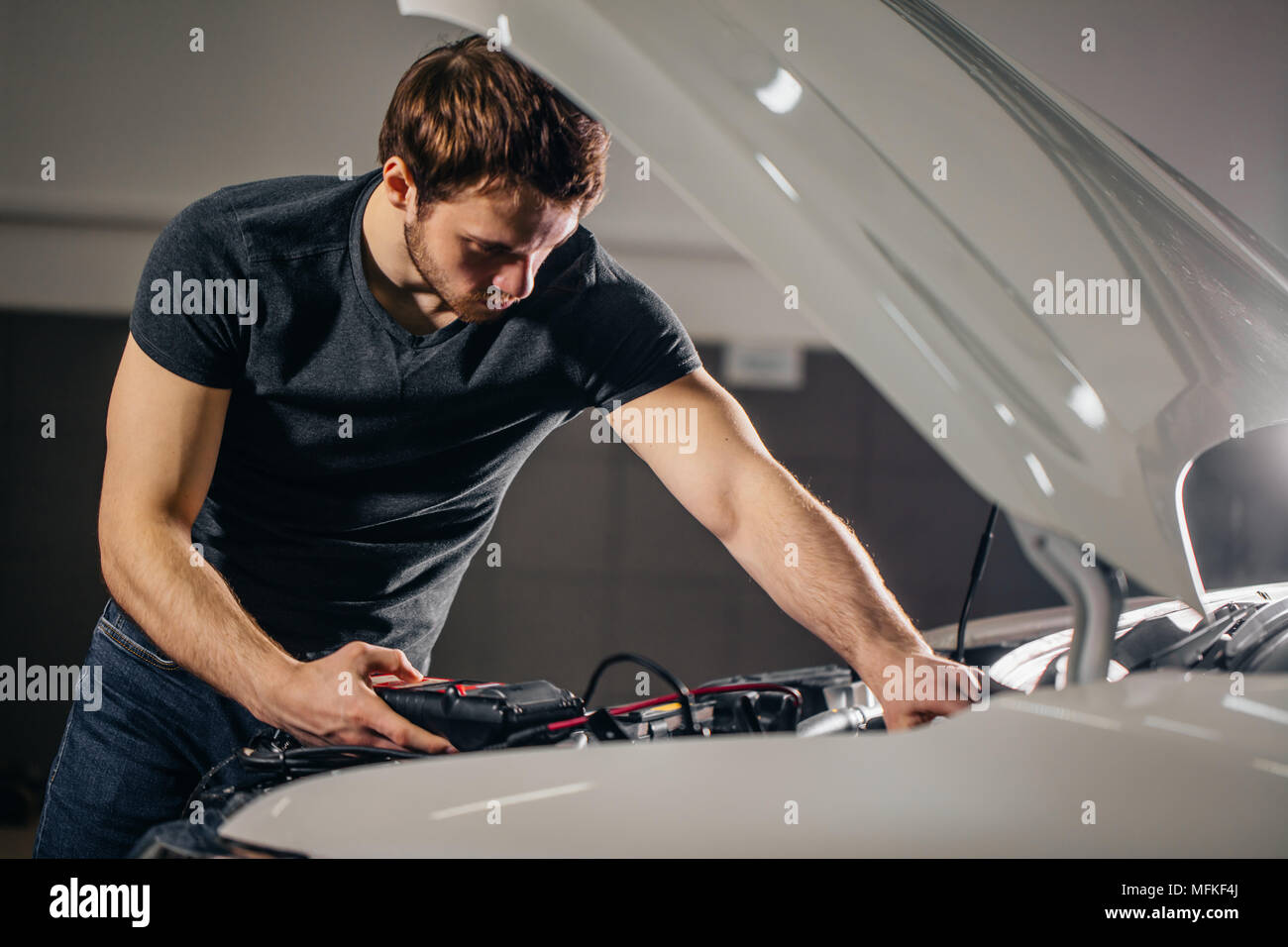 Car mechanic using electrical tool for testing car system in garage ...
