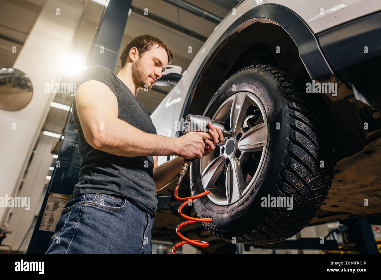 Mechanic changing wheel on car with pneumatic tool Stock Photo - Alamy