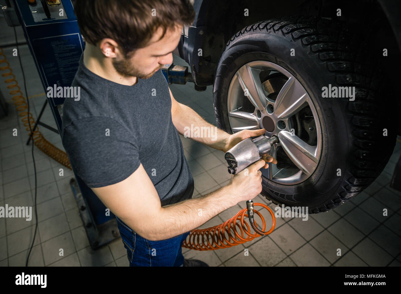 Mechanic changing wheel on car with pneumatic tool Stock Photo - Alamy