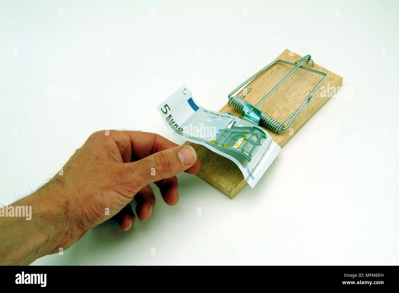Hand carefully approaching a mouse trap baited with a five Euro note ...